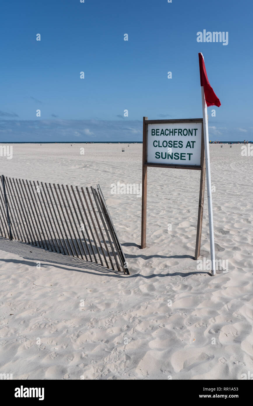 vertical Beachfront closes at sunset sign on white sand beach with ...