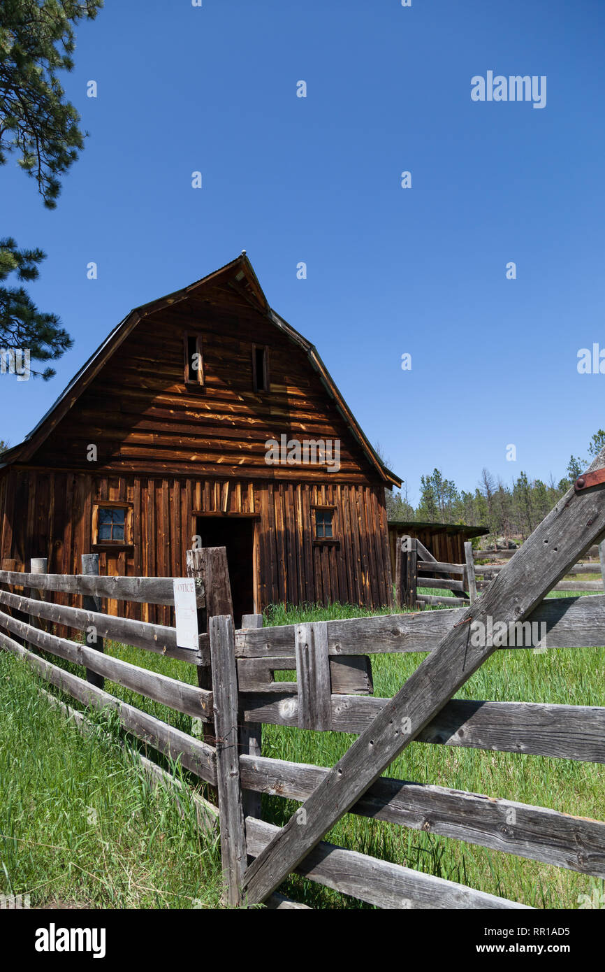 An old wooden barn with a fenced in corral and tall green grass on an ...