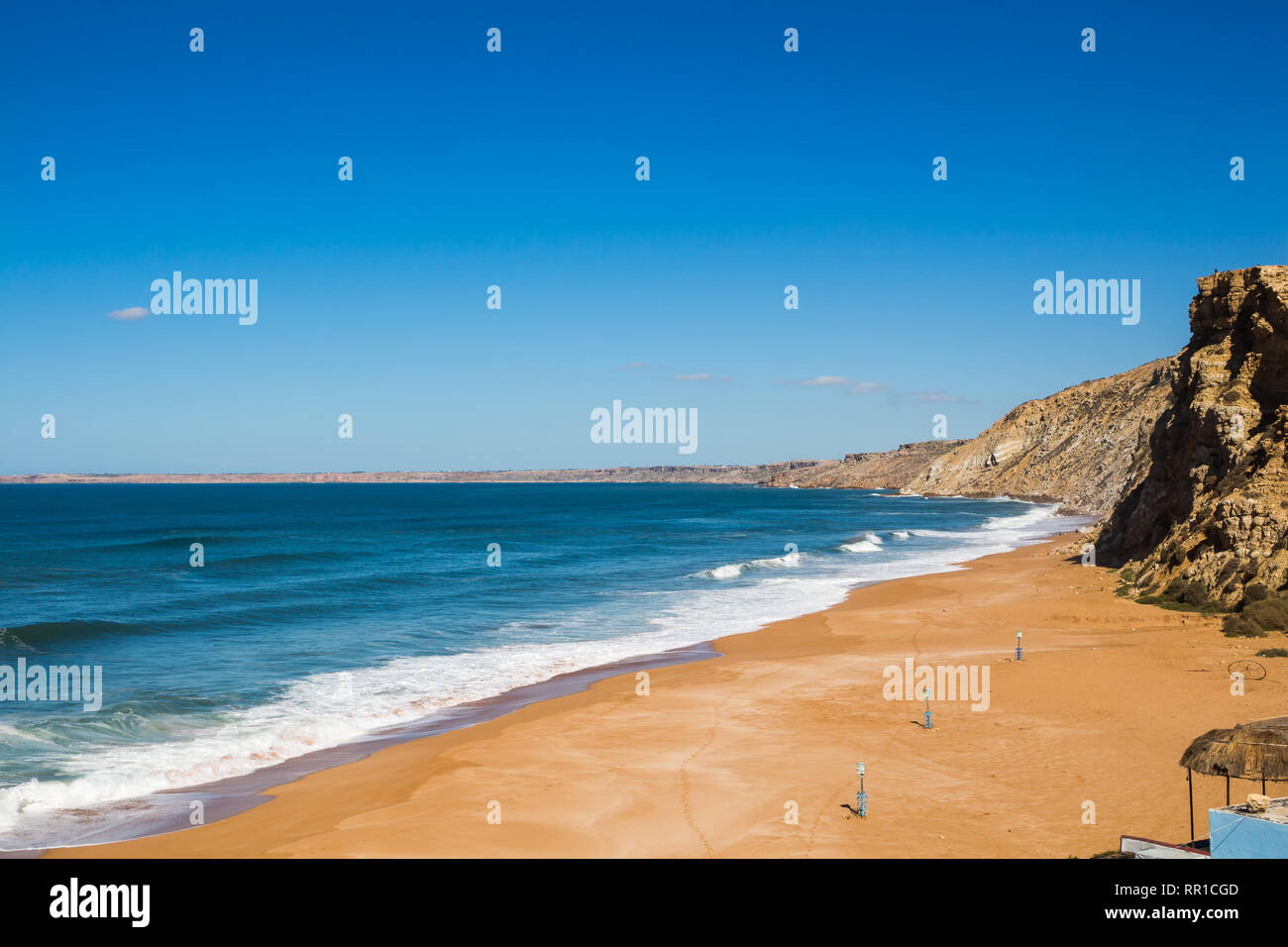 Dark yellow color of the sandy beach, lined by rocky mountain. Waves of ...