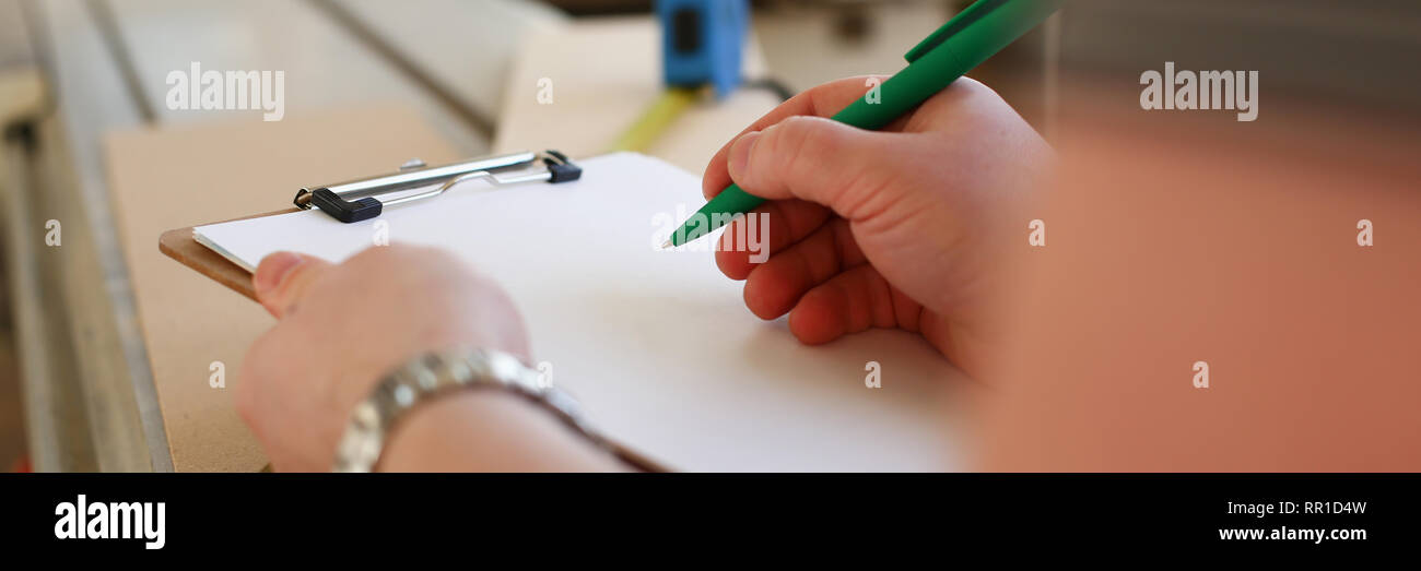 Arms of worker making notes on clipboard with green pen Stock Photo - Alamy