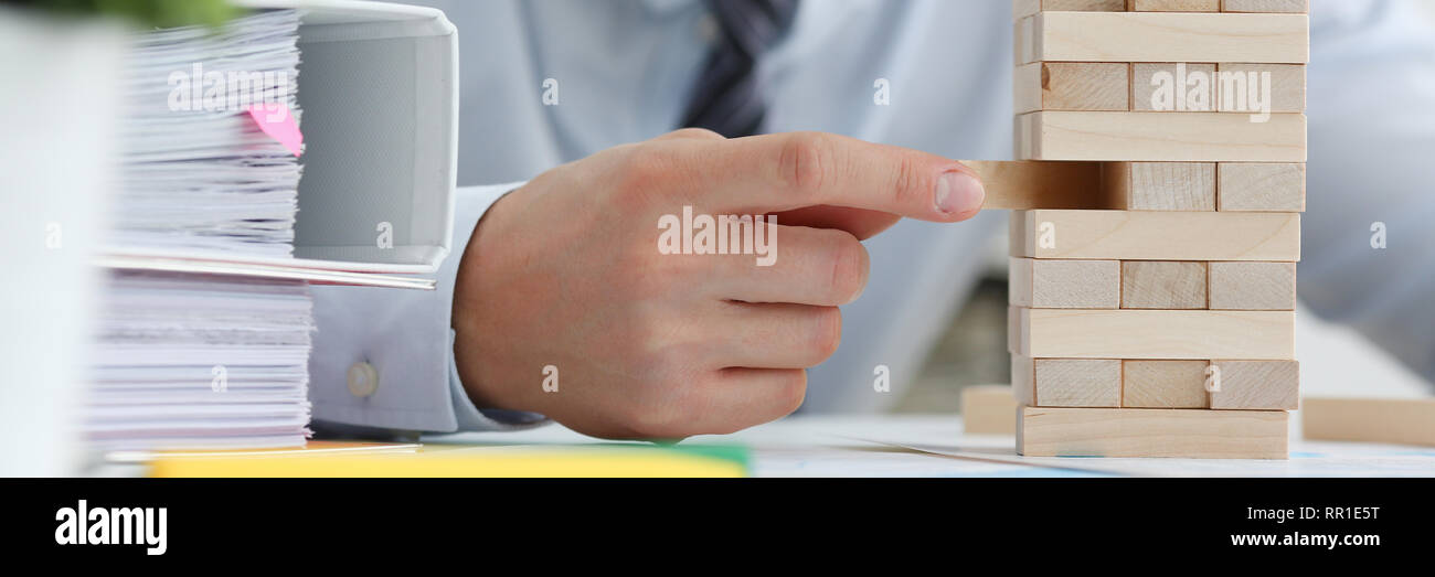 Businessman plays in a strategy of jenga hand Stock Photo - Alamy