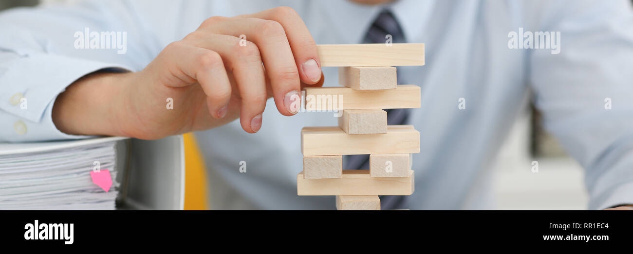 Businessman plays in a strategy of jenga hand Stock Photo - Alamy