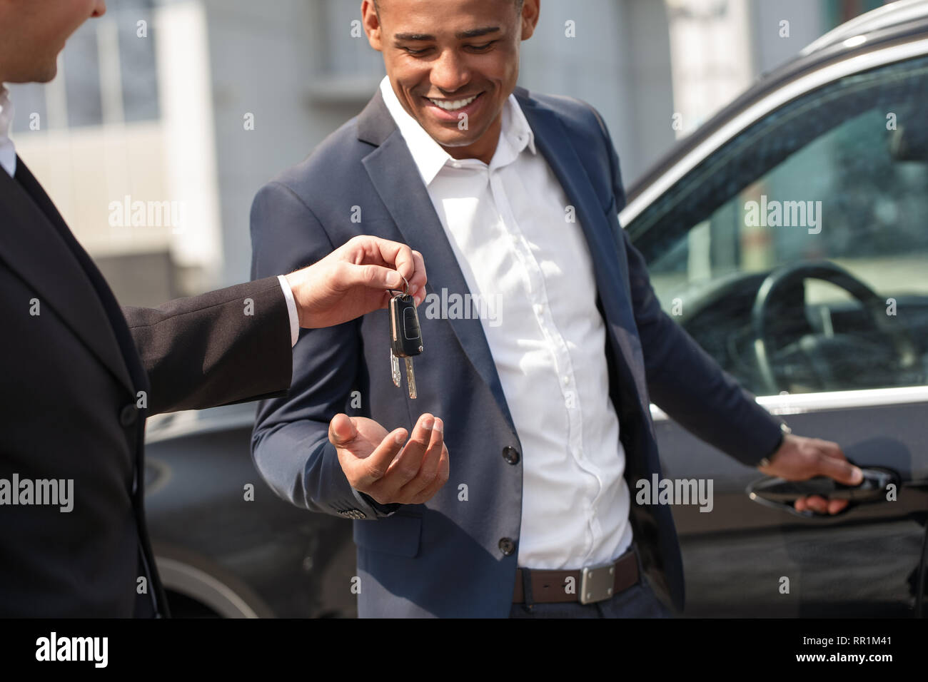 Agent giving keys to young man opening door standing near car happy ...