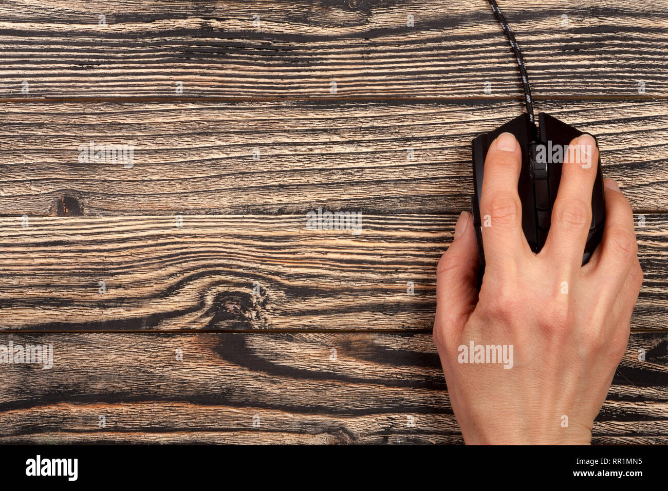 black computer mouse with a hand on a black wooden background with copy ...
