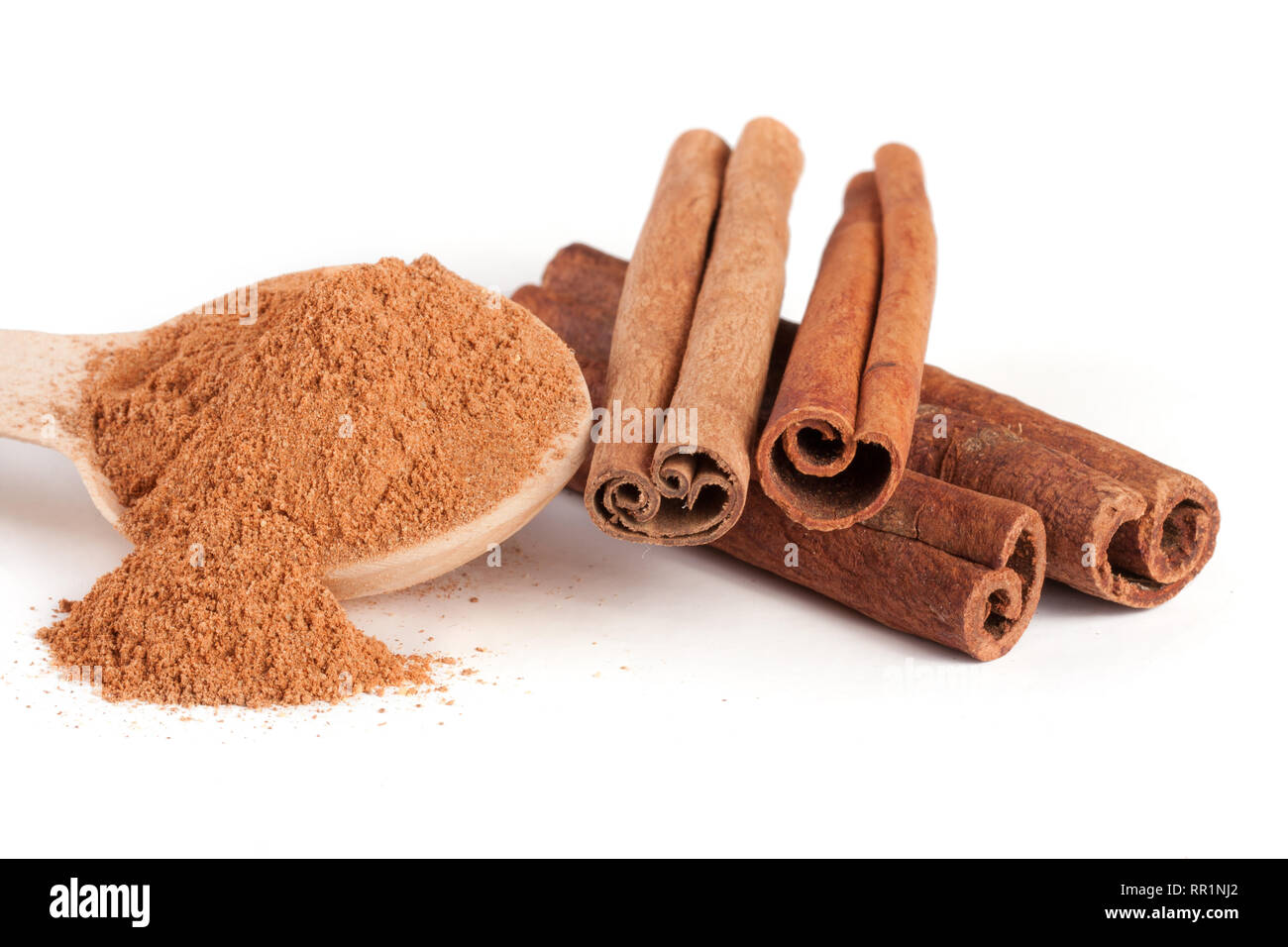 three cinnamon sticks and powder with spoon isolated on white ...