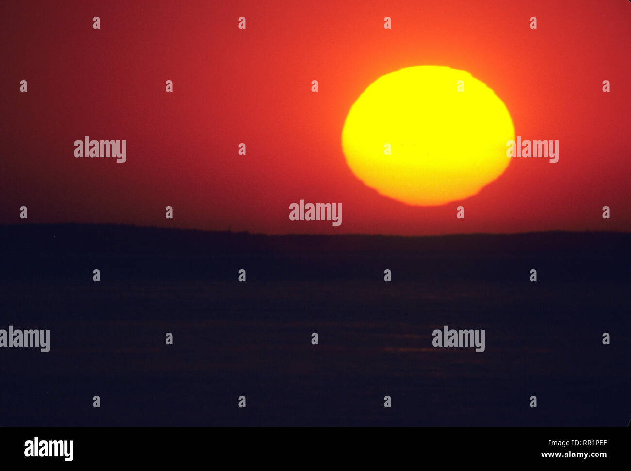 The setting sun as seen through a long telephoto lens over Cape Cod Bay ...