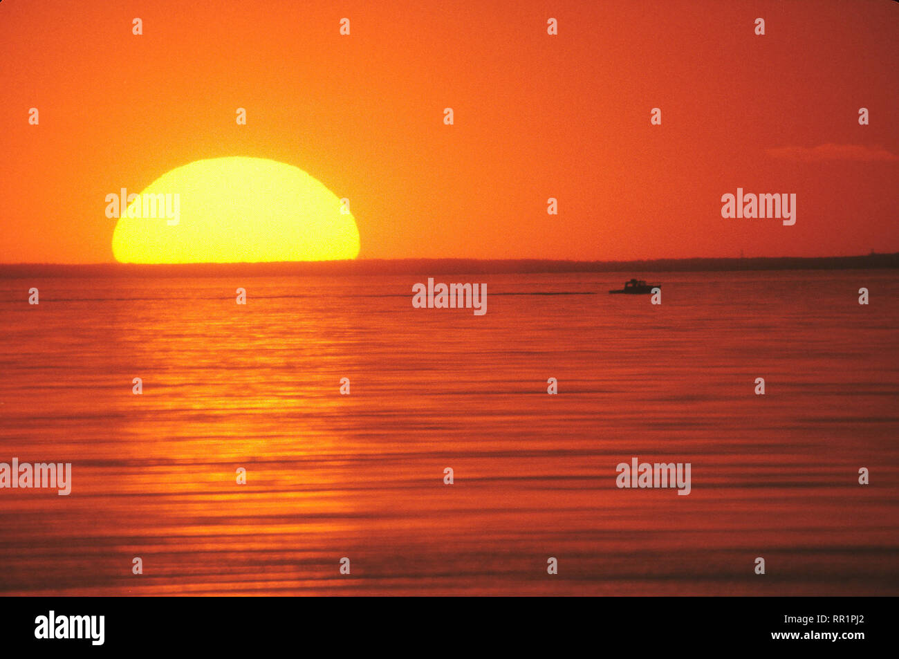 The setting sun as seen through a long telephoto lens over Cape Cod Bay ...