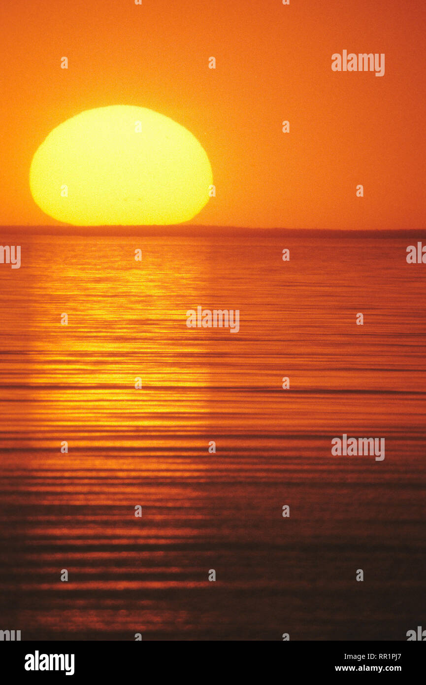 The setting sun as seen through a long telephoto lens over Cape Cod Bay ...