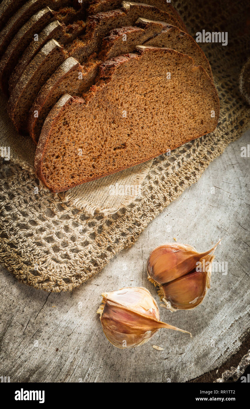 Fresh rye sliced bread on natural linen napkin and garlic cloves on ...