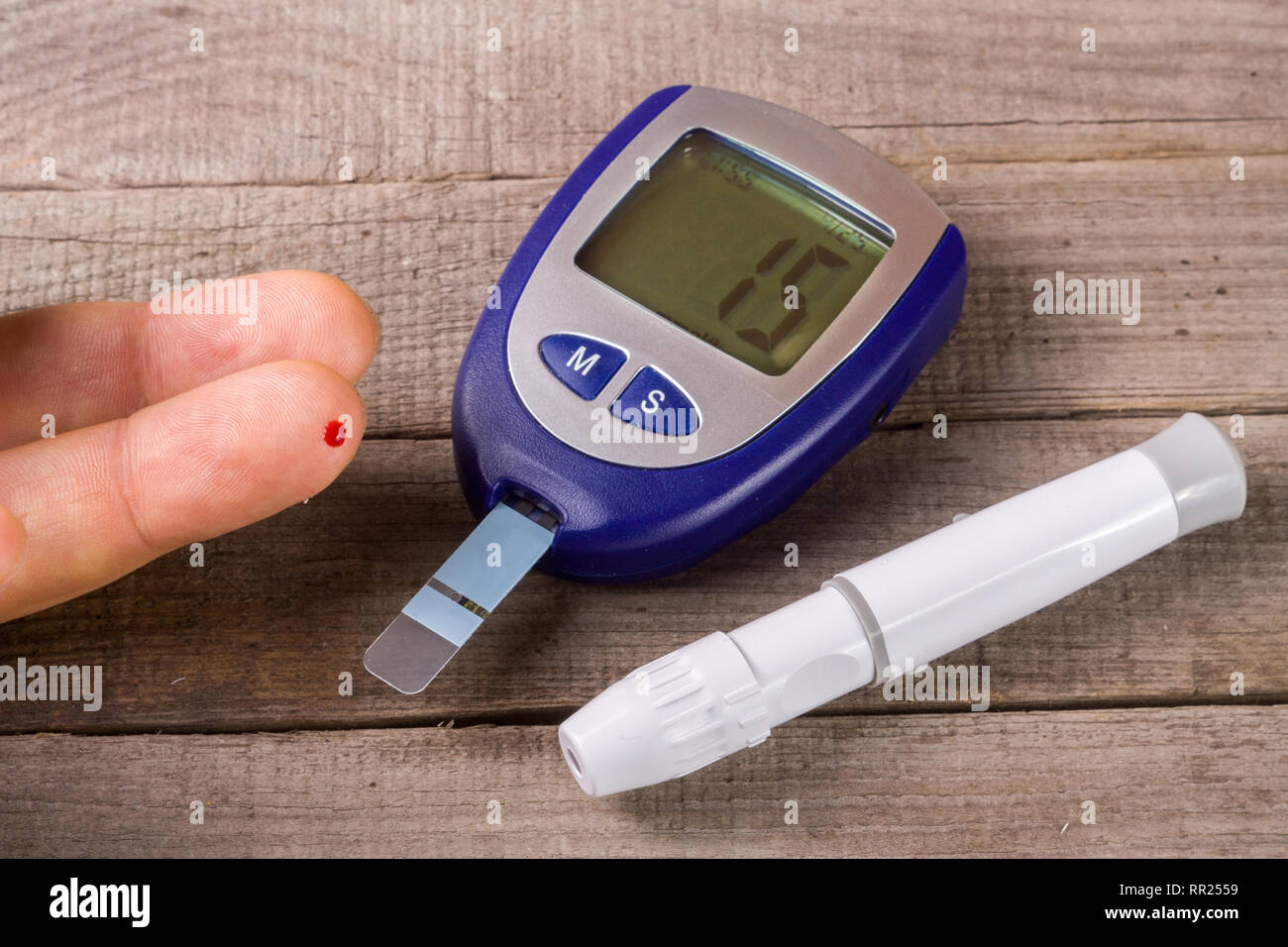 blood glucose meter with a hand on an old wooden background Stock Photo ...