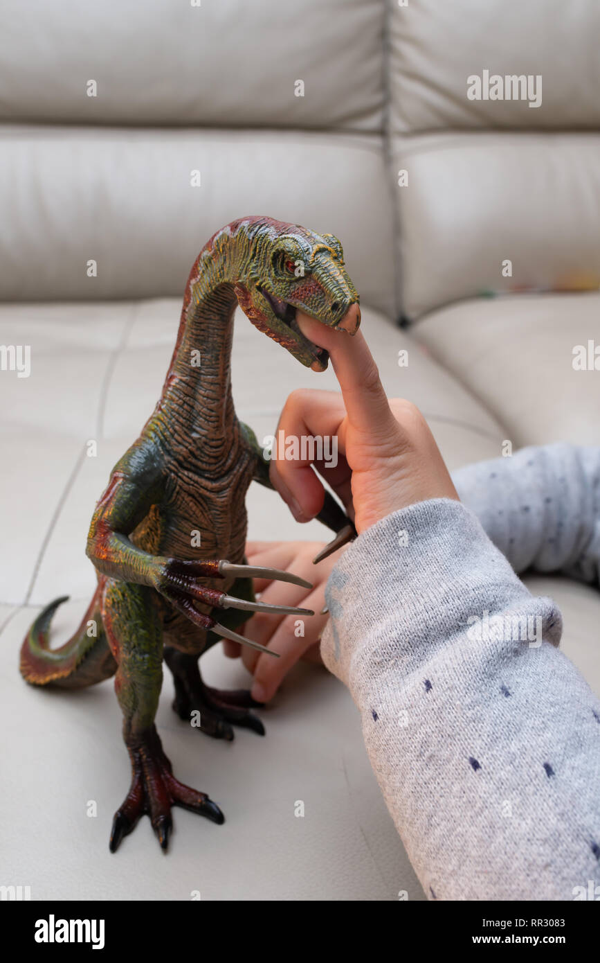 kid playing a nothronychus toy and putting his finger inside the mouth ...