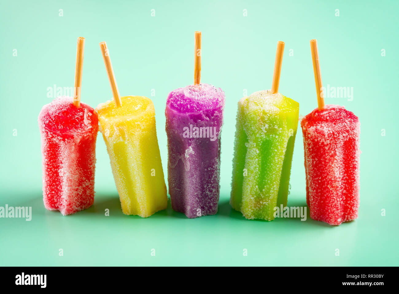 side view multi-color popsicles line up on green background Stock Photo ...