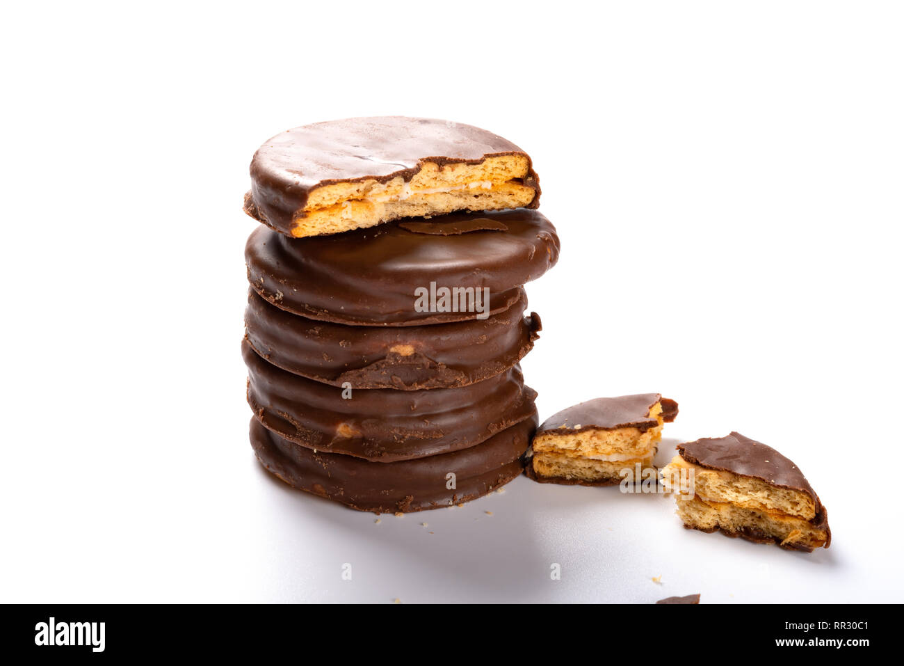 chocolate outer biscuits stacked up with one piece broken on white ...