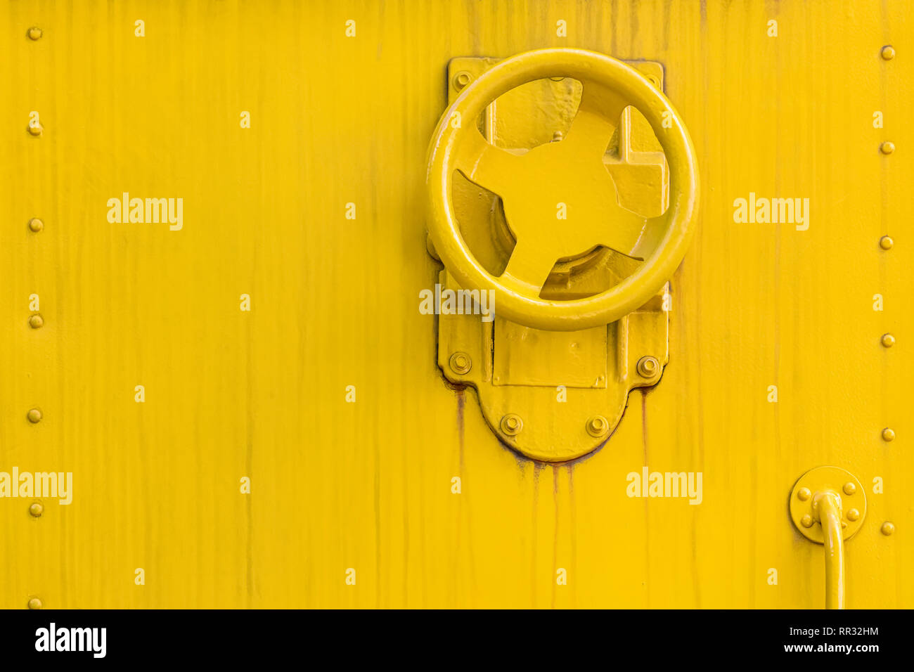 weathered yellow painted metal surface background with valve wheel ...