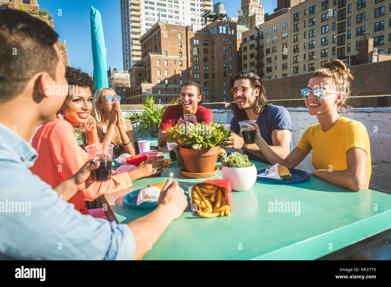 Young happy people having a barbecue dinner on a rooftop in New York ...