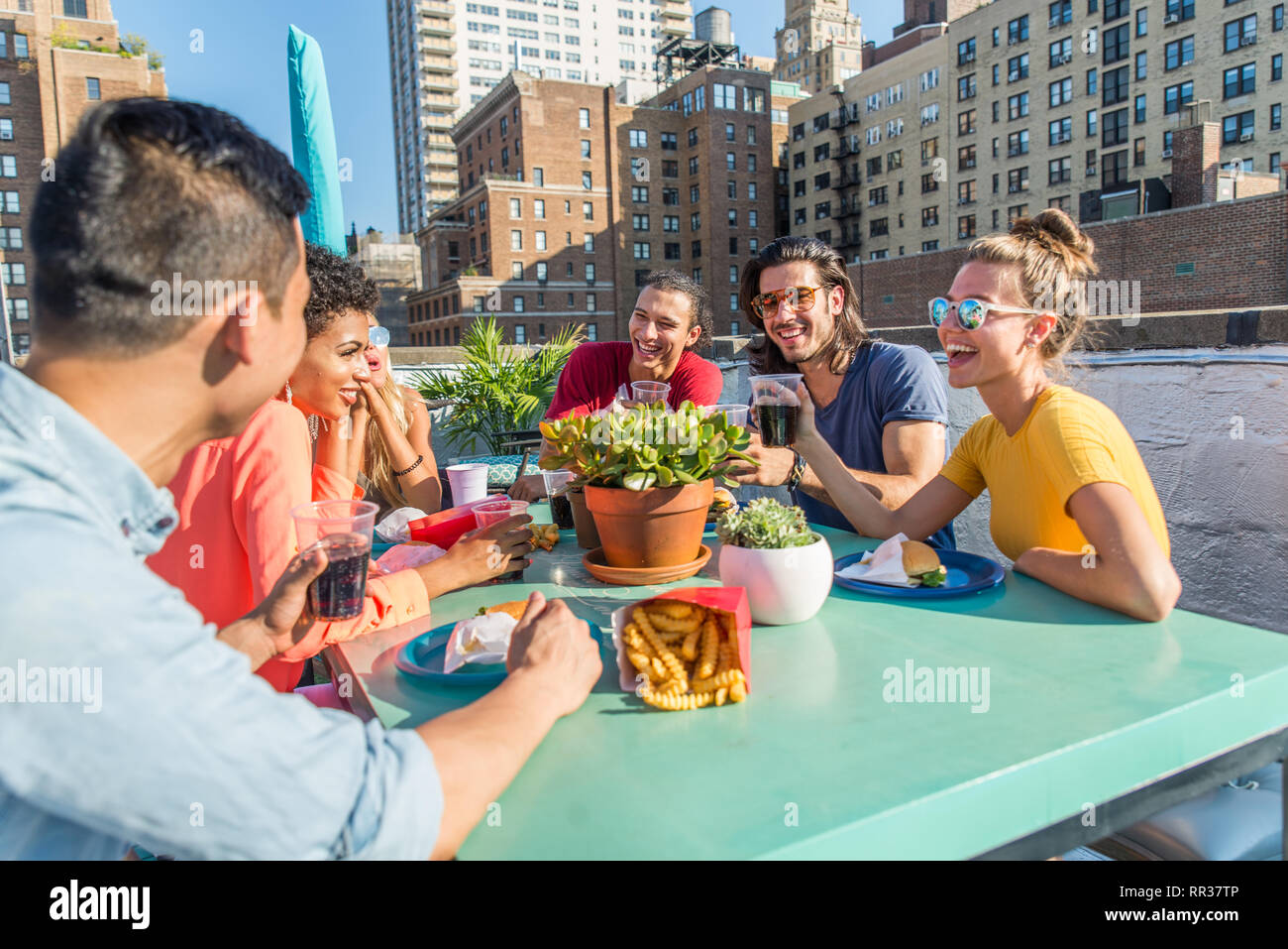 Young happy people having a barbecue dinner on a rooftop in New York ...
