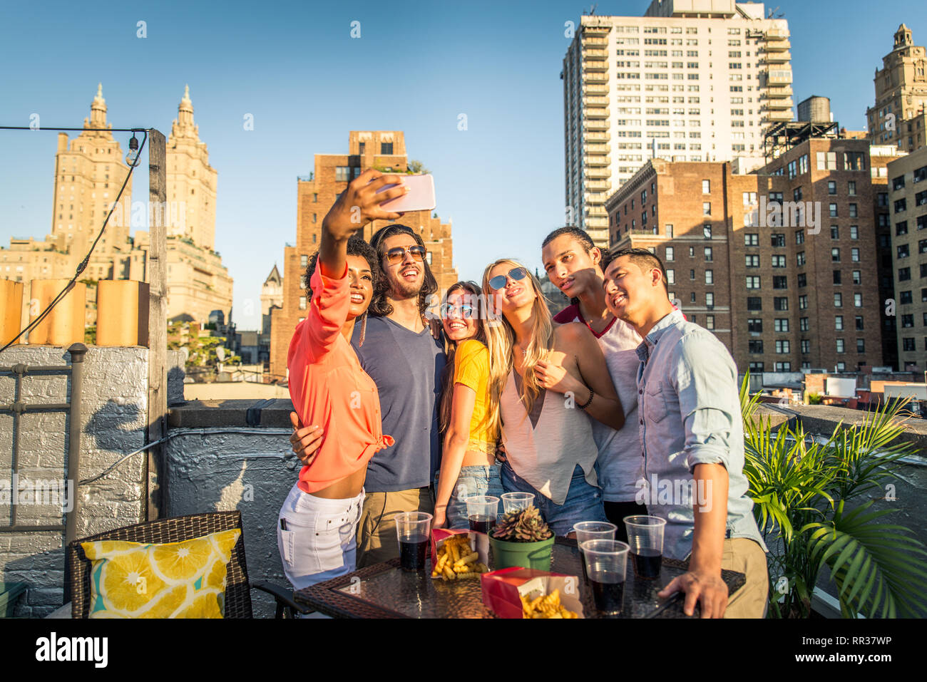 Young happy people having a barbecue dinner on a rooftop in New York ...