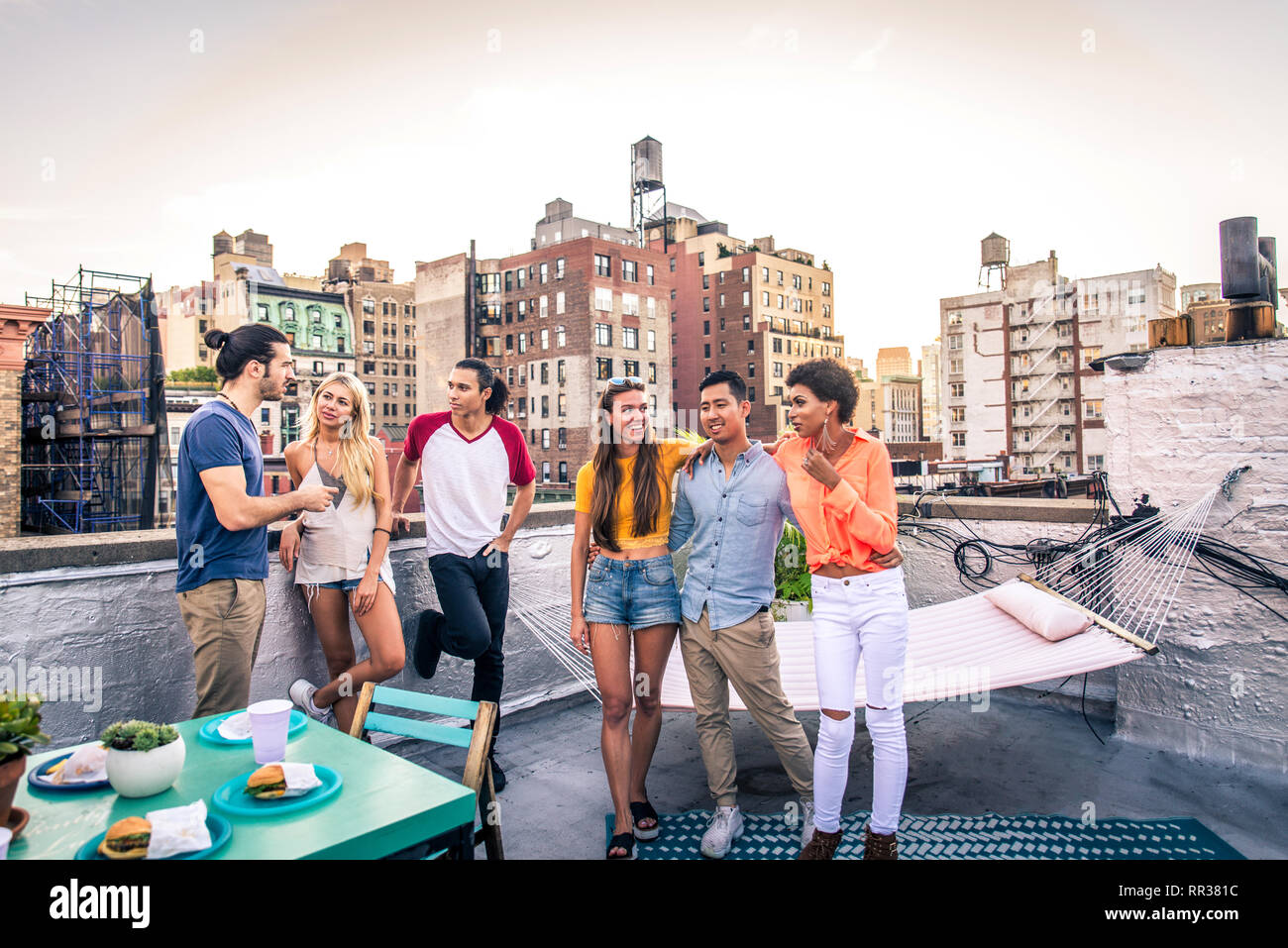 Young happy people having a barbecue dinner on a rooftop in New York ...