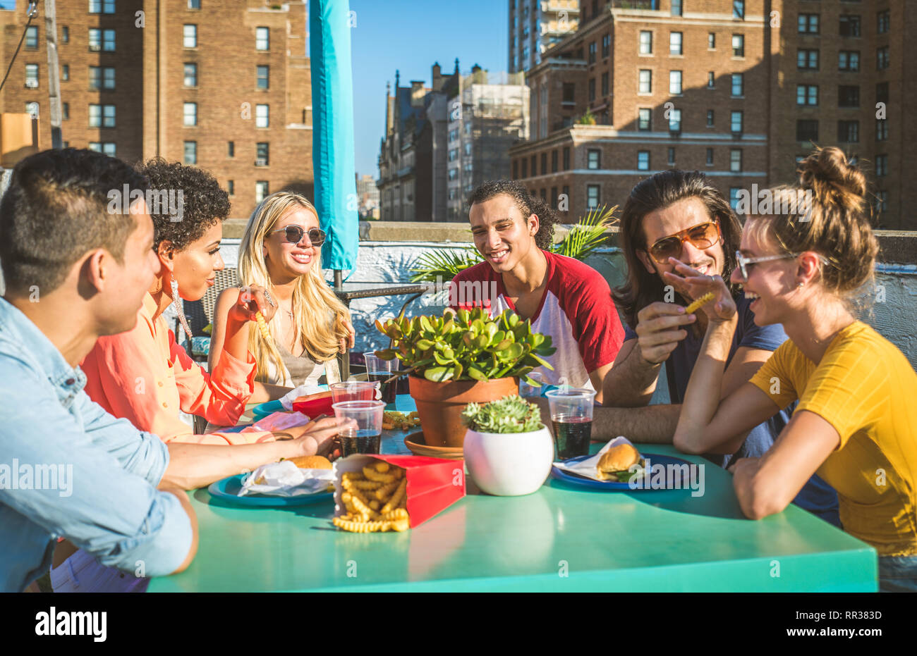 Young happy people having a barbecue dinner on a rooftop in New York ...