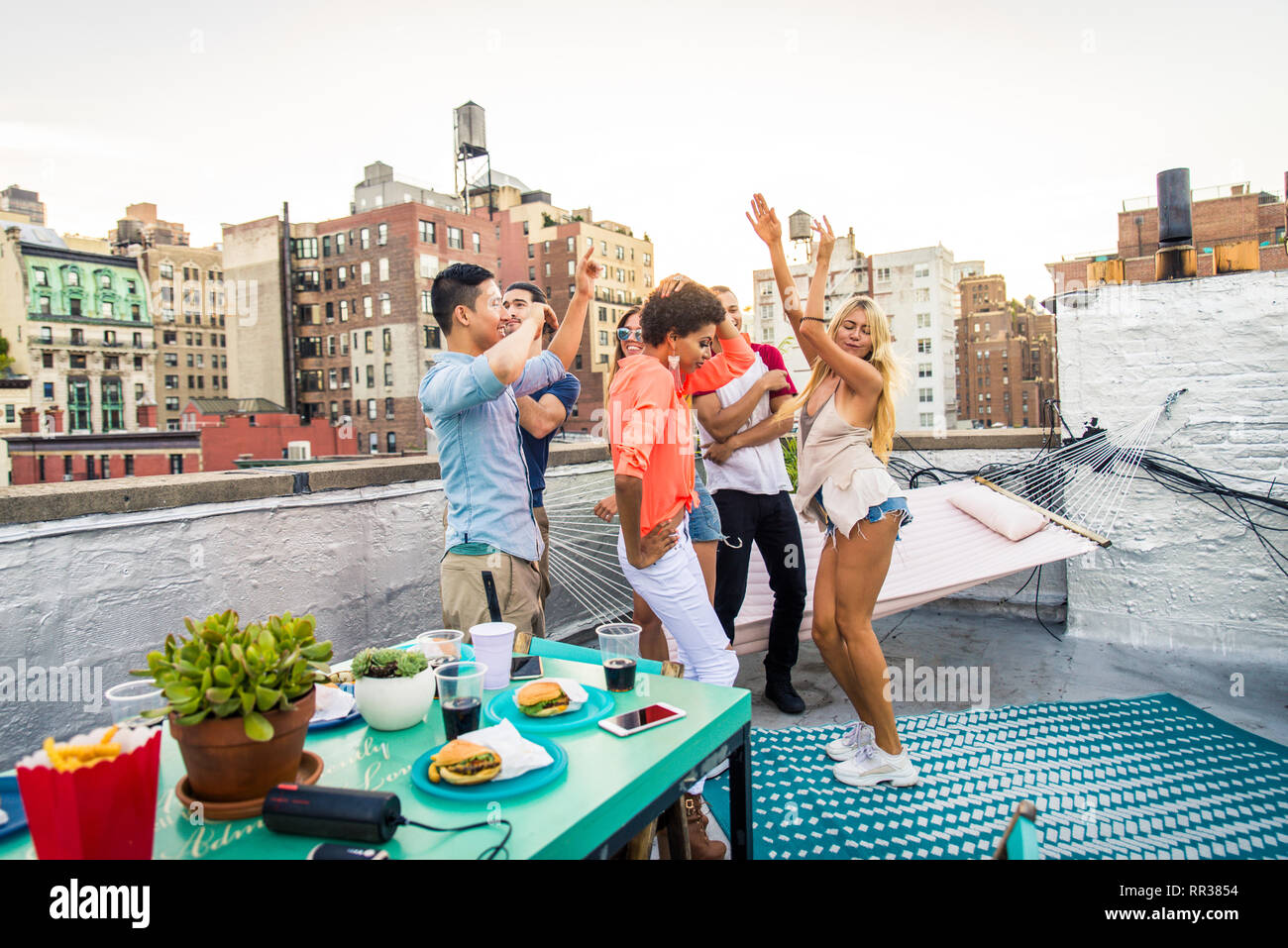 Young happy people having a barbecue dinner on a rooftop in New York ...
