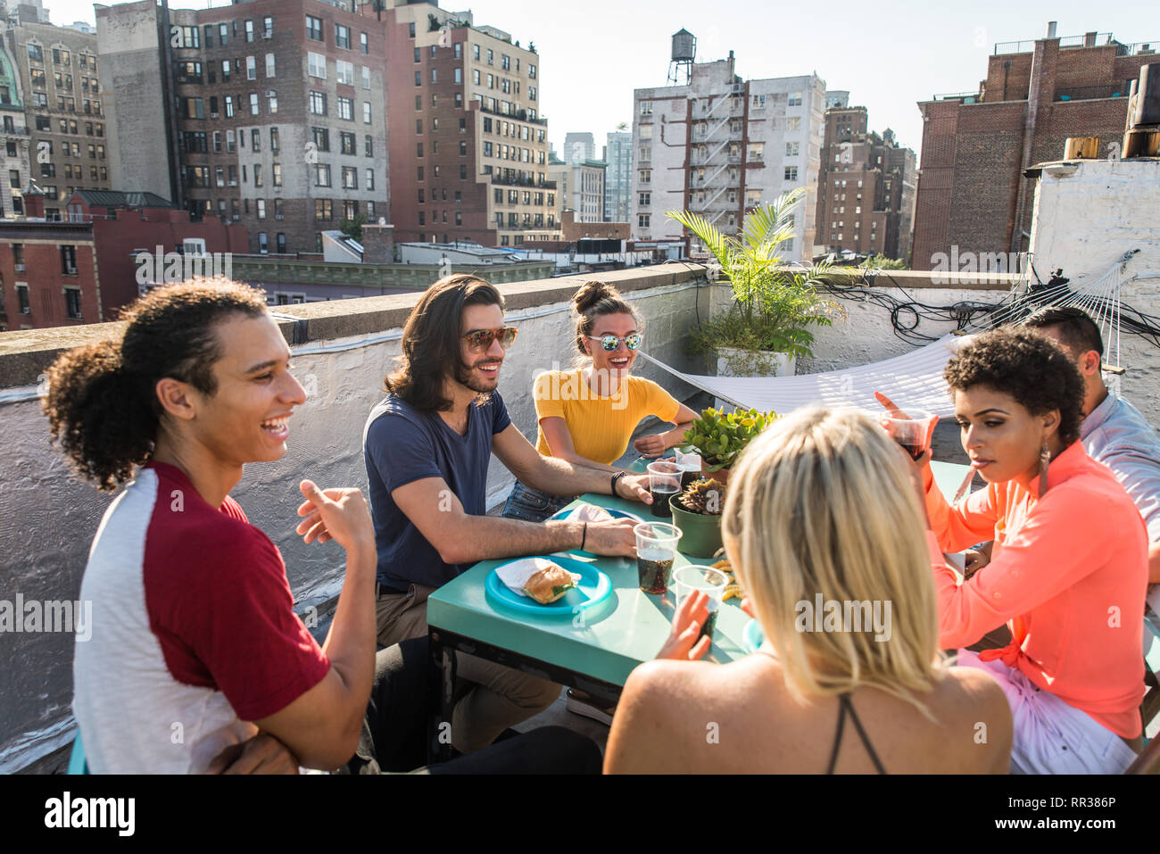 Young happy people having a barbecue dinner on a rooftop in New York ...