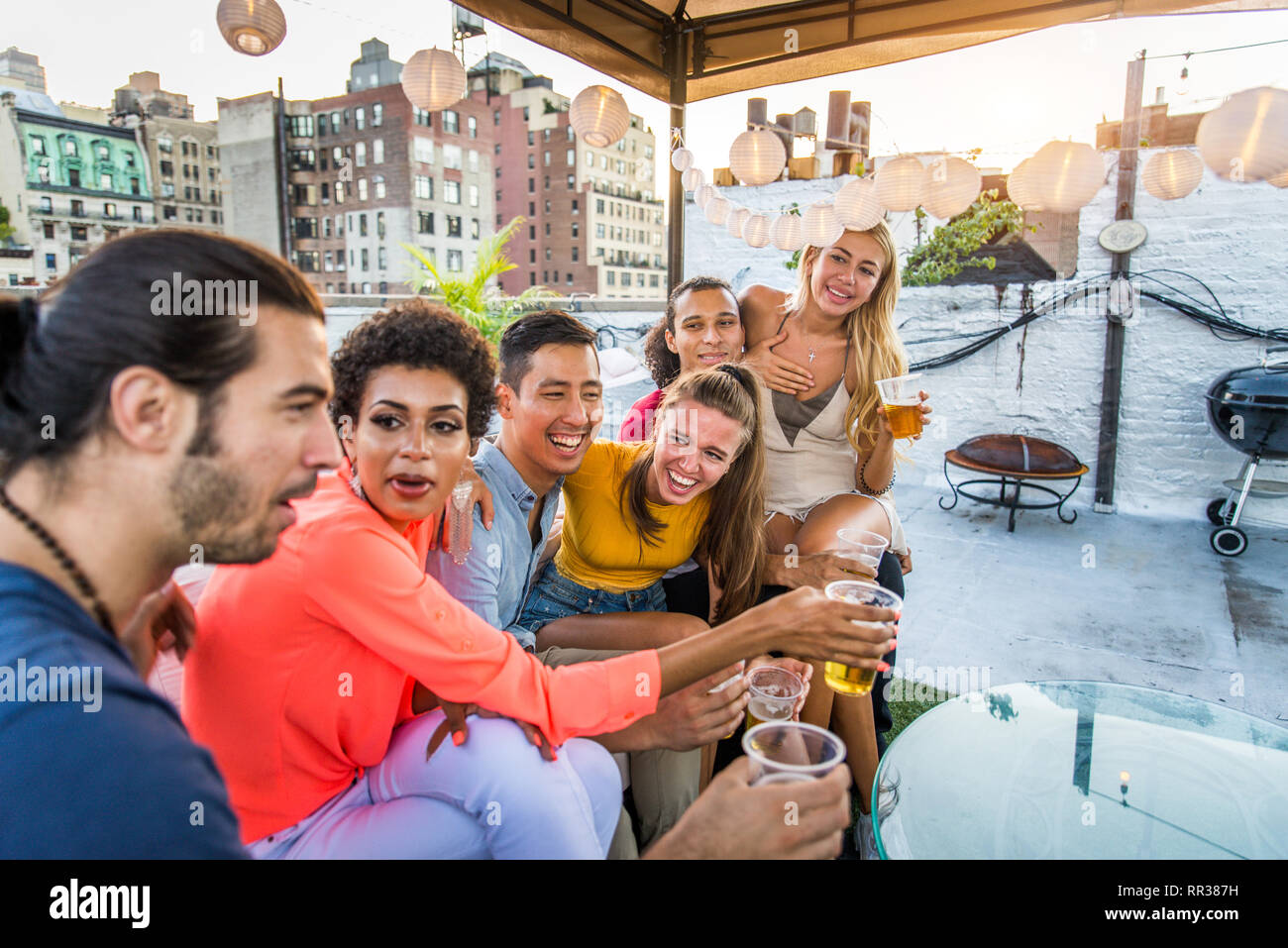 Young happy people having a barbecue dinner on a rooftop in New York ...