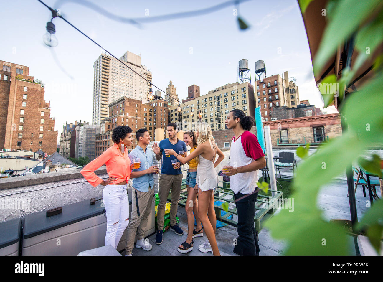 Young happy people having a barbecue dinner on a rooftop in New York ...