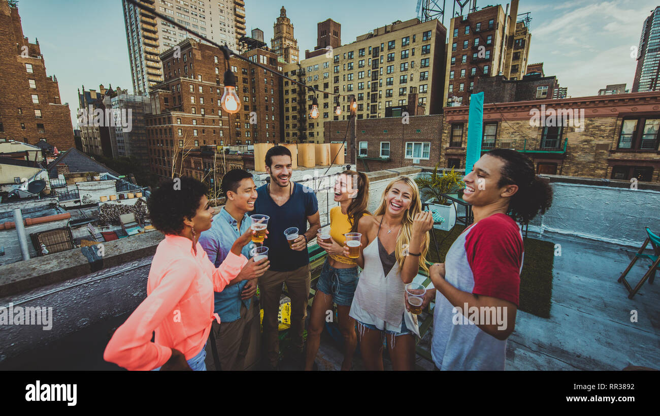 Young happy people having a barbecue dinner on a rooftop in New York ...