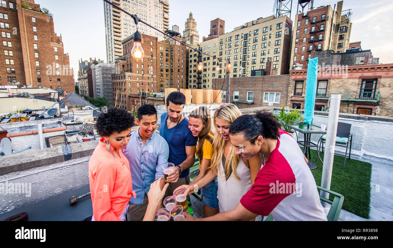 Young happy people having a barbecue dinner on a rooftop in New York ...
