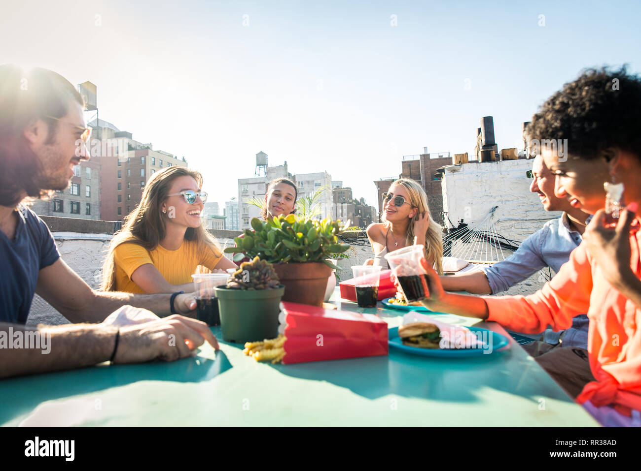 Young happy people having a barbecue dinner on a rooftop in New York ...
