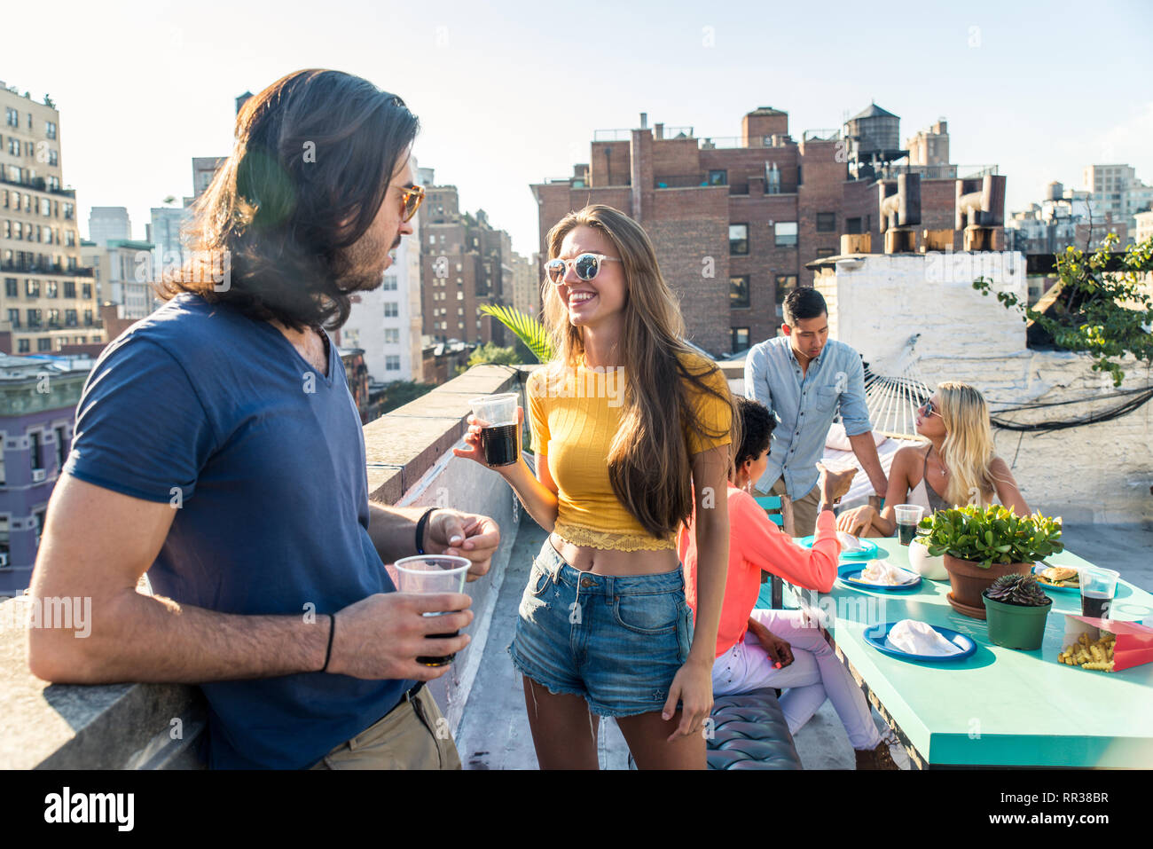 Young happy people having a barbecue dinner on a rooftop in New York ...