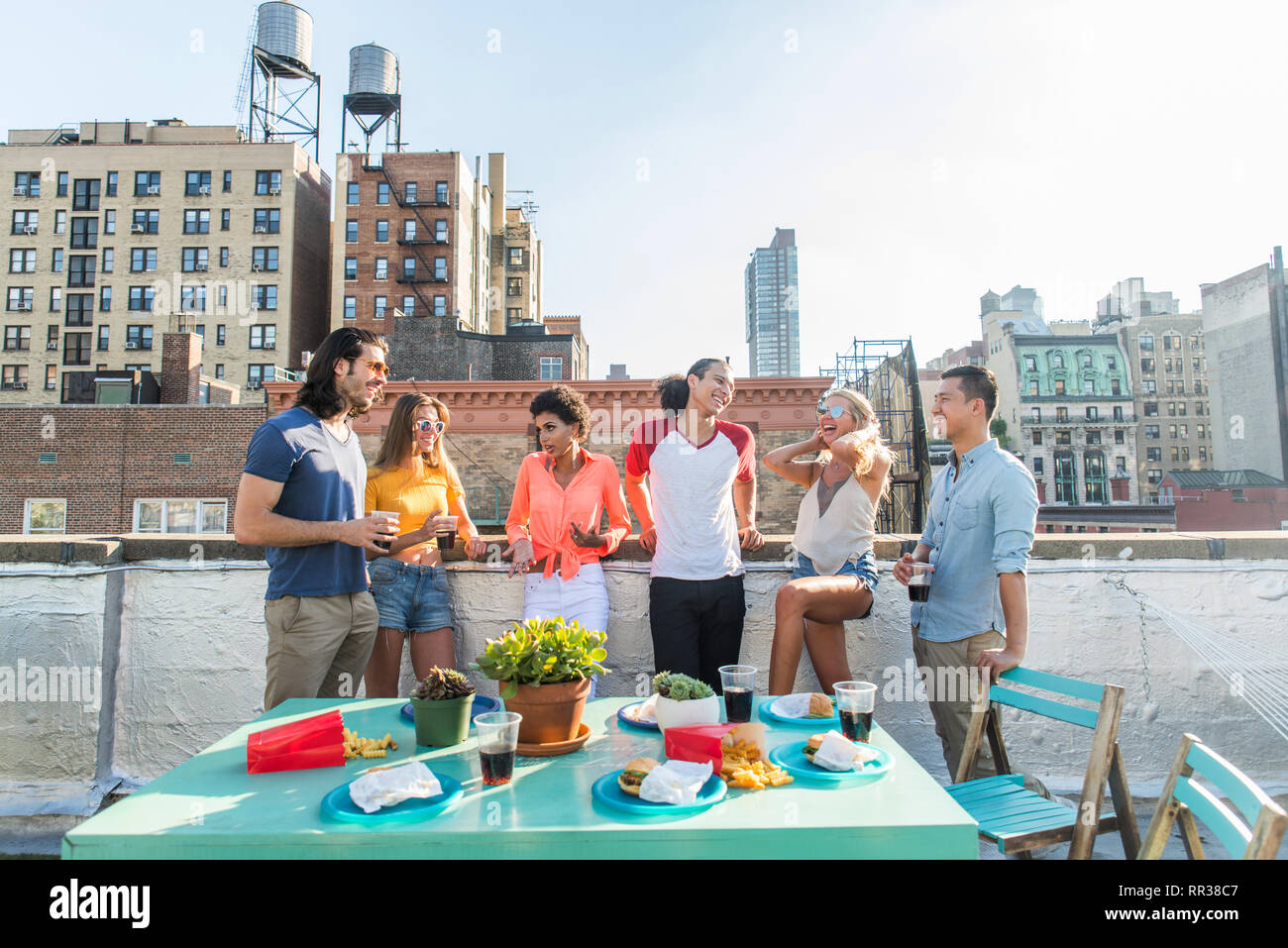 Young happy people having a barbecue dinner on a rooftop in New York ...