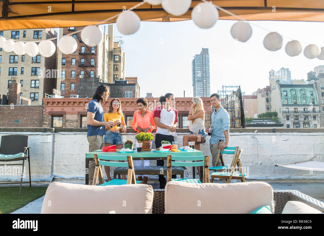 Young happy people having a barbecue dinner on a rooftop in New York ...