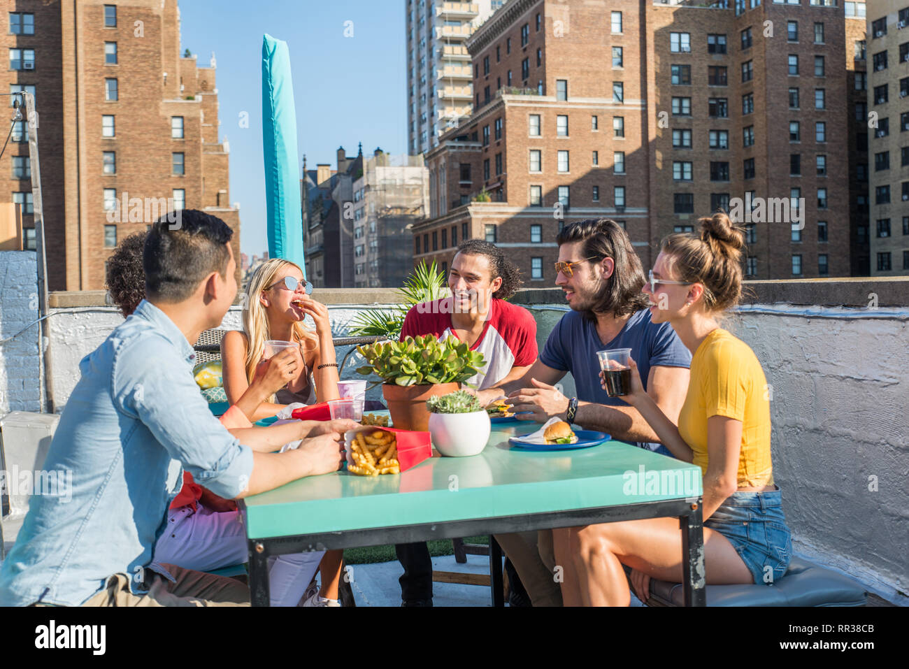 Young happy people having a barbecue dinner on a rooftop in New York ...