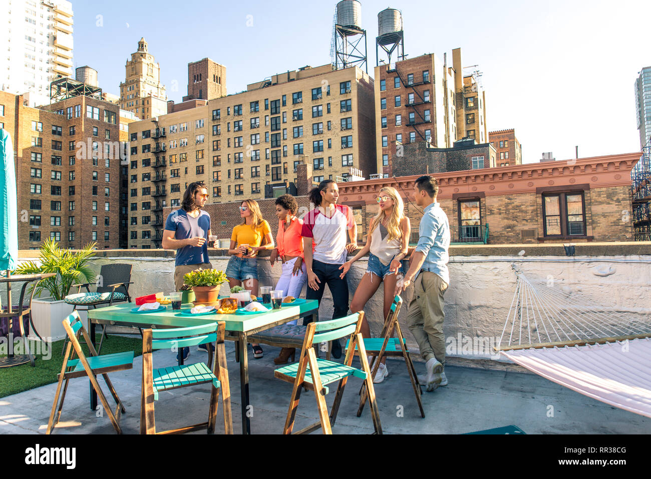 Young happy people having a barbecue dinner on a rooftop in New York ...