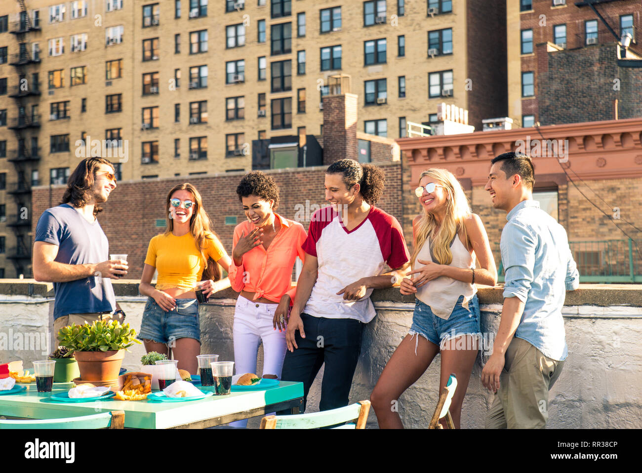Young happy people having a barbecue dinner on a rooftop in New York ...