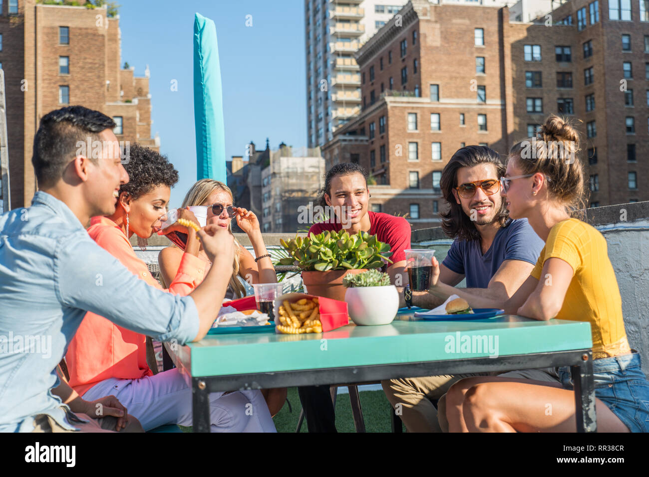 Young happy people having a barbecue dinner on a rooftop in New York ...