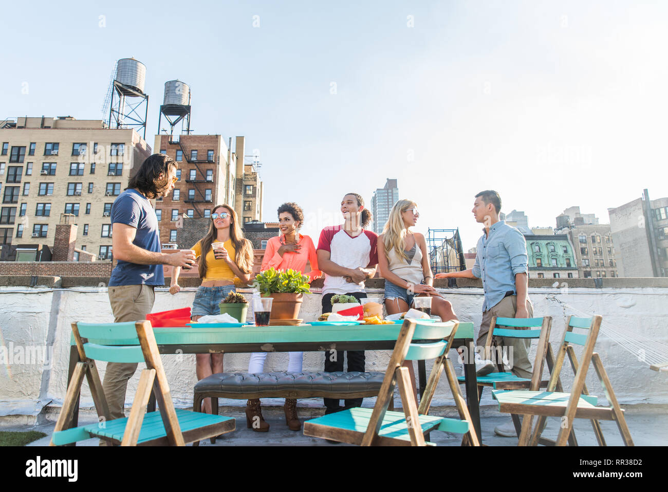 Young happy people having a barbecue dinner on a rooftop in New York ...