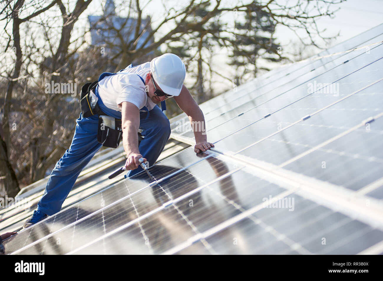 Male worker installing solar photovoltaic panel system using ...