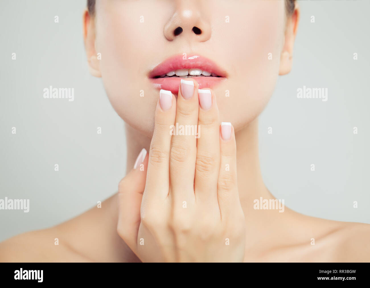 Manicured hand with french manicure and pink glossy lips. Woman face ...