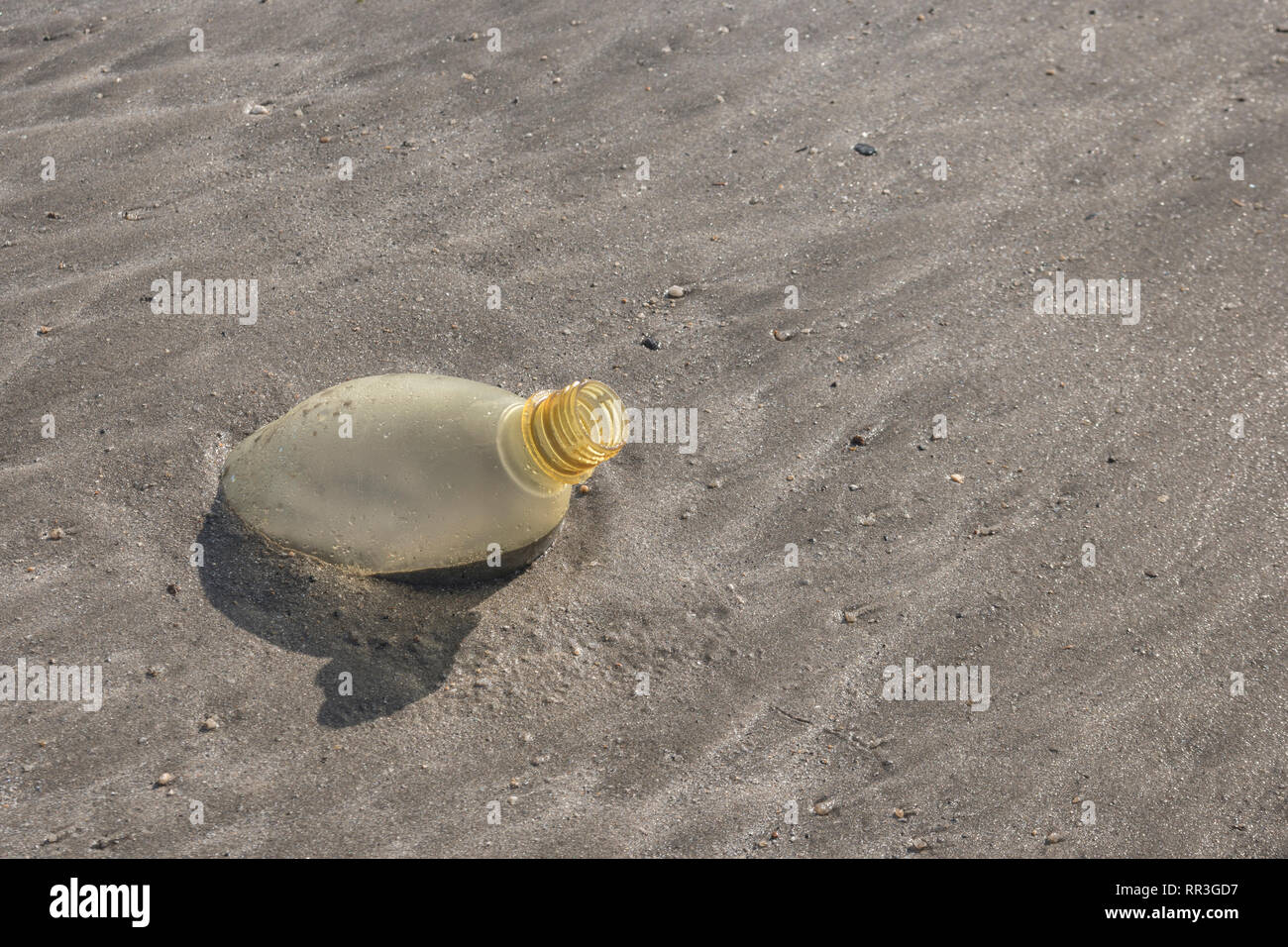 Empty plastic soft drink bottle embedded in silty beach sand. For ...
