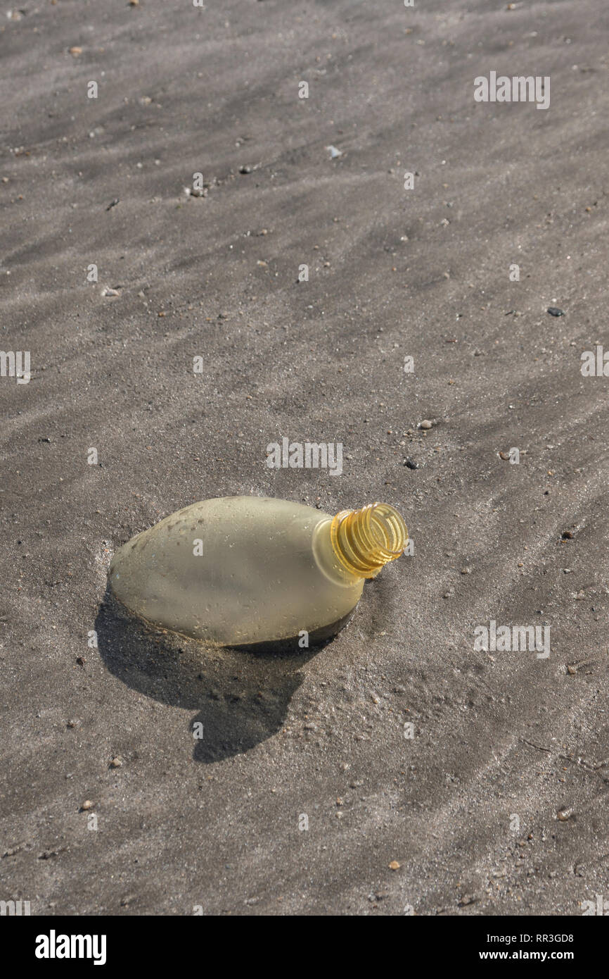 Empty plastic soft drink bottle embedded in silty beach sand. For ...