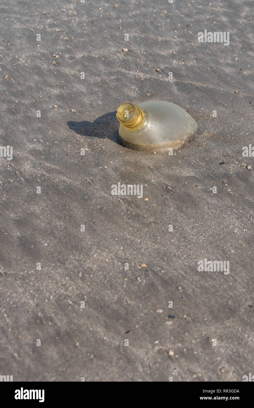 Empty plastic soft drink bottle embedded in silty beach sand. For ...