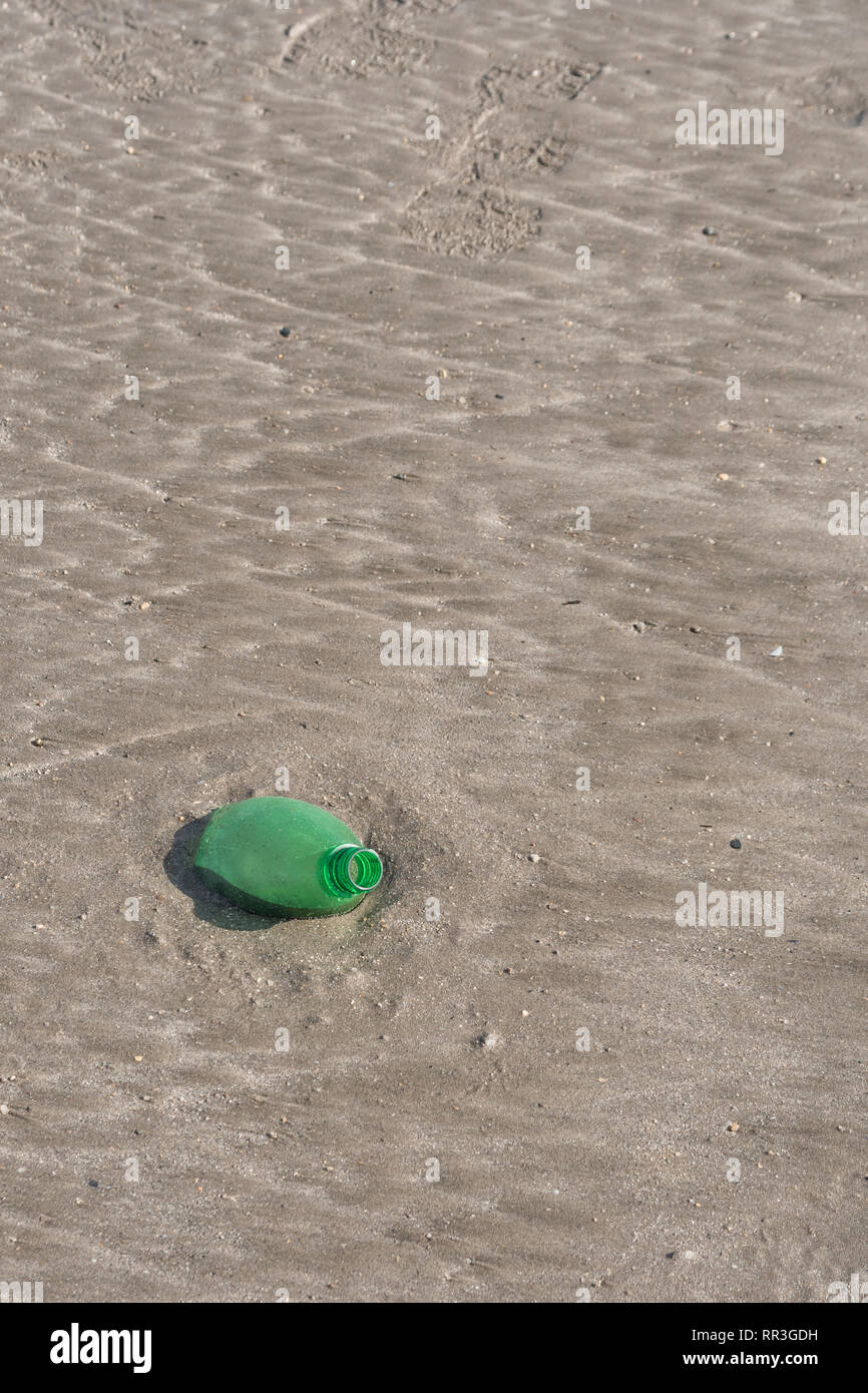 Empty plastic soft drink bottle embedded in silty beach sand. For ...