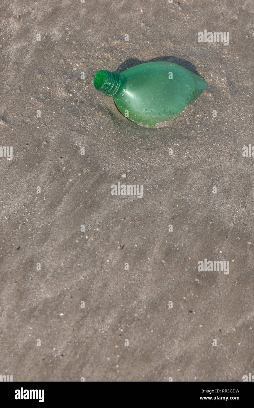 Empty plastic soft drink bottle embedded in silty beach sand. For ...