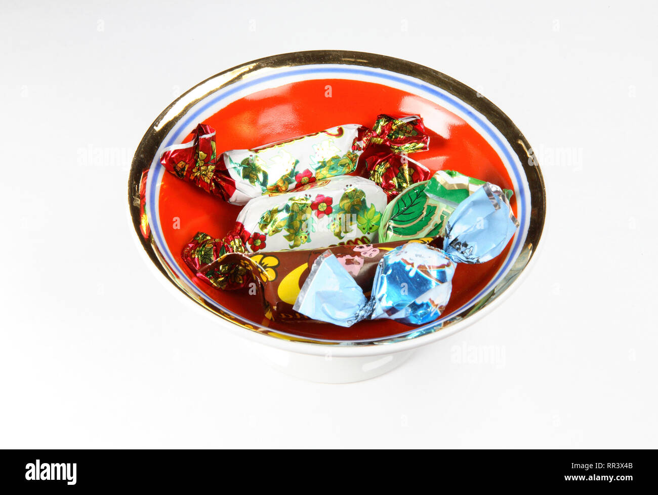 set of candies in sweet wrapper on red saucer Stock Photo - Alamy