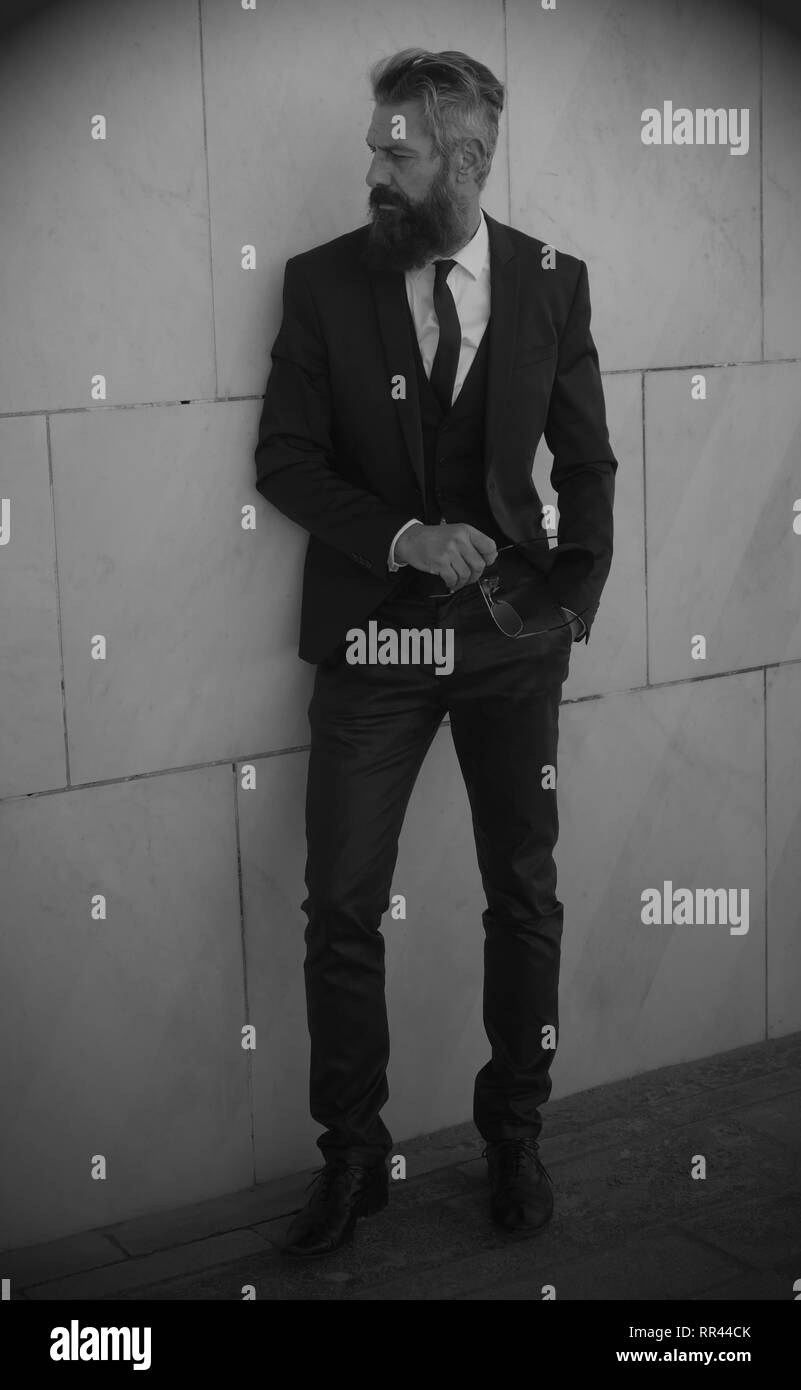 smart man with black costume standing front wall Stock Photo - Alamy