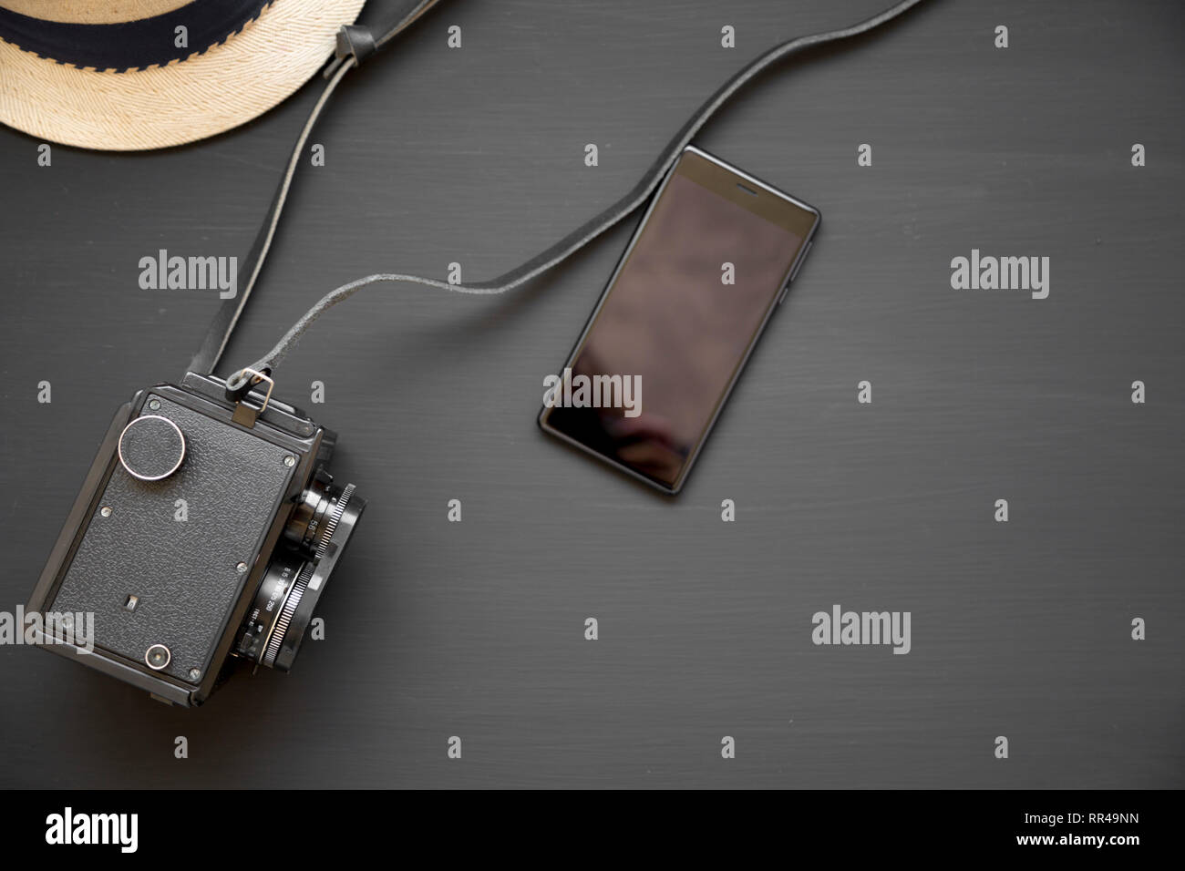 Vintage camera, hat and smartphone on black background, overhead view ...
