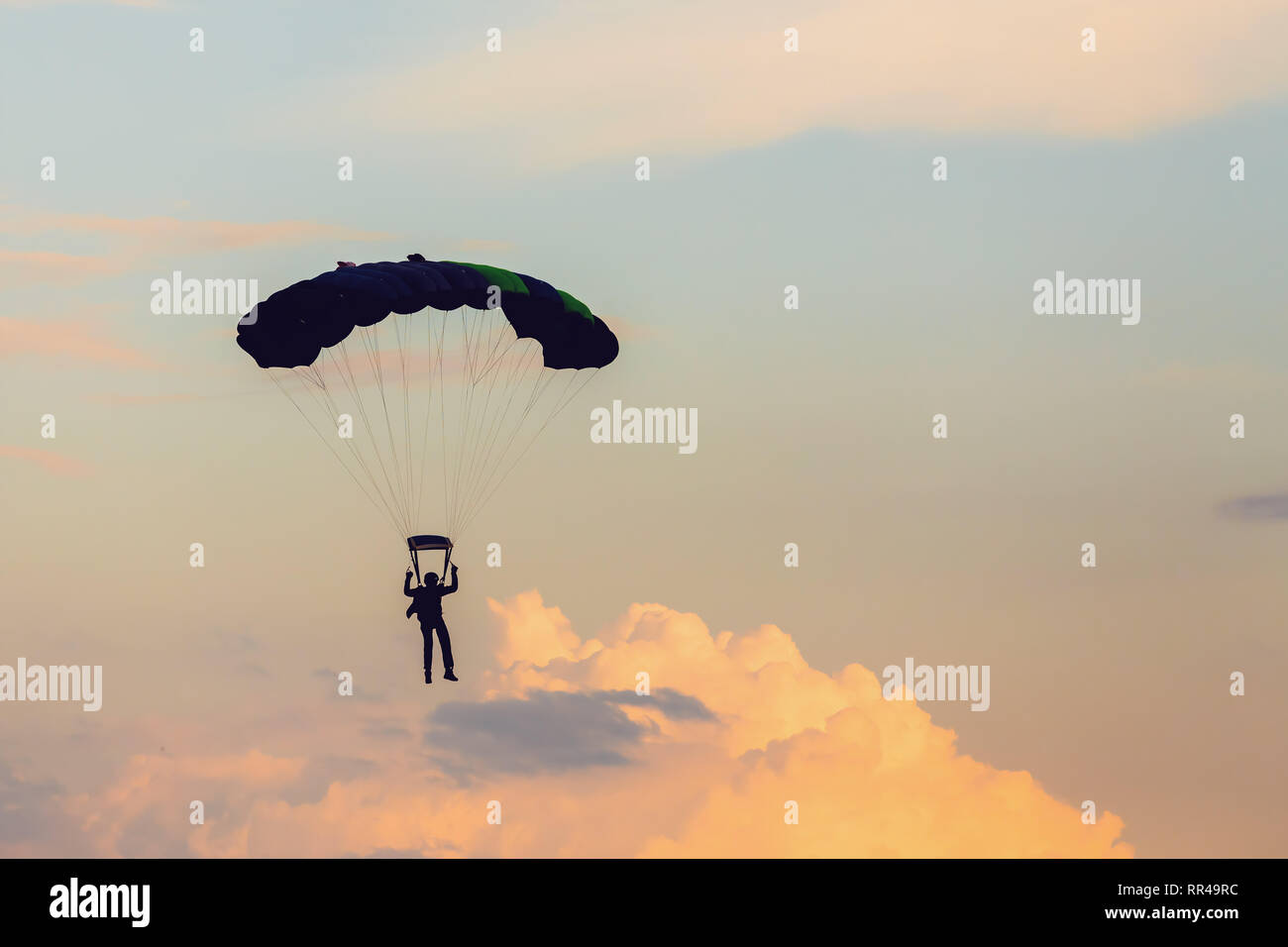 Parachutist falling from the sky in evening sunset dramatic sky ...