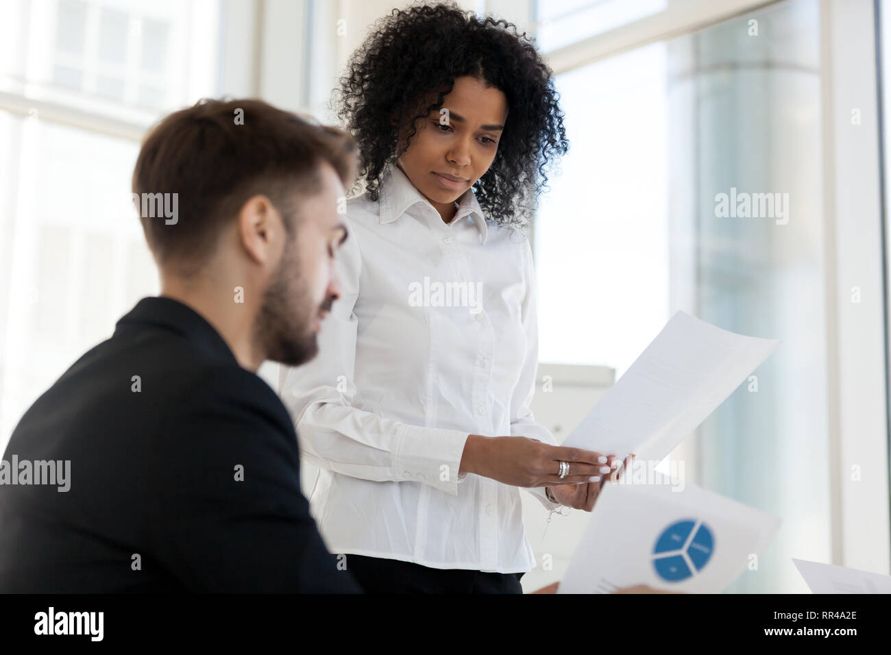 Team leader and colleague looking at statistics shown on document Stock ...